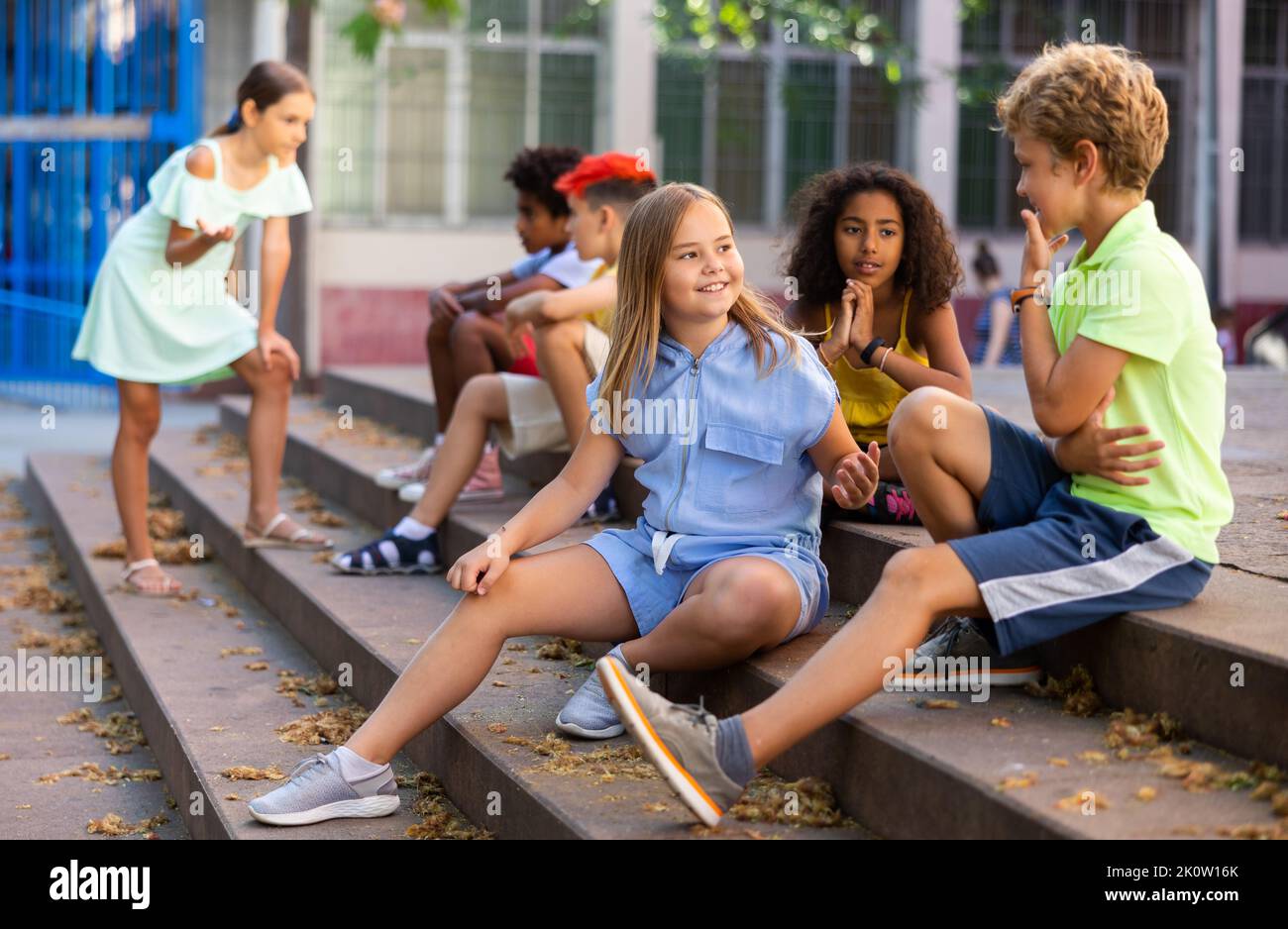 Children talking together while sitting on stairs outdoors Stock Photo ...