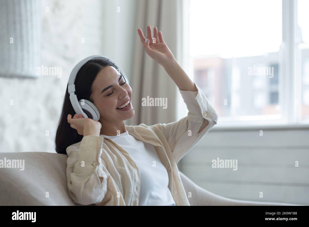 Beautiful young woman listening to music in white headphones. He sits ...