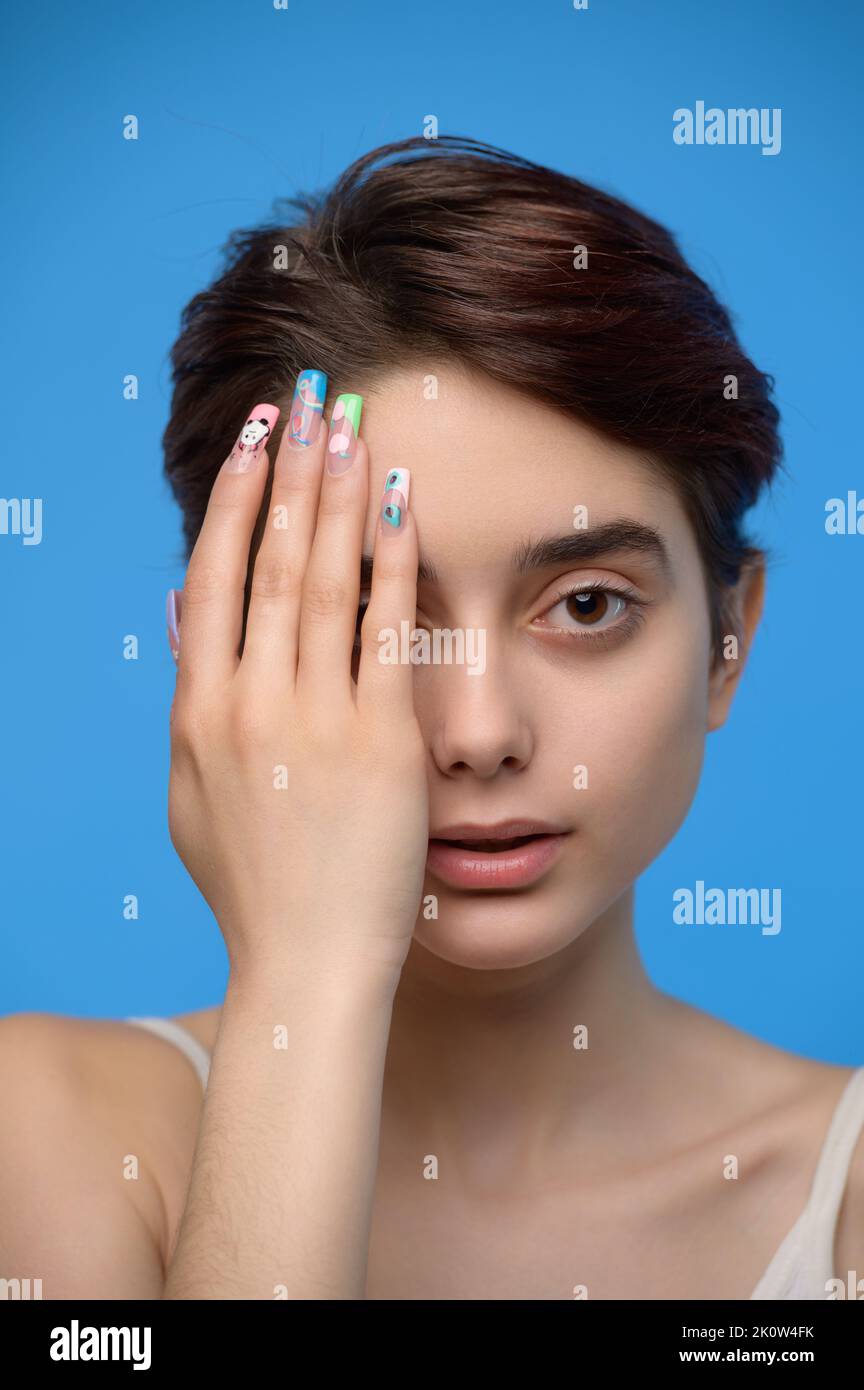 A beautiful young brunette with her palm covering the right side of her ...