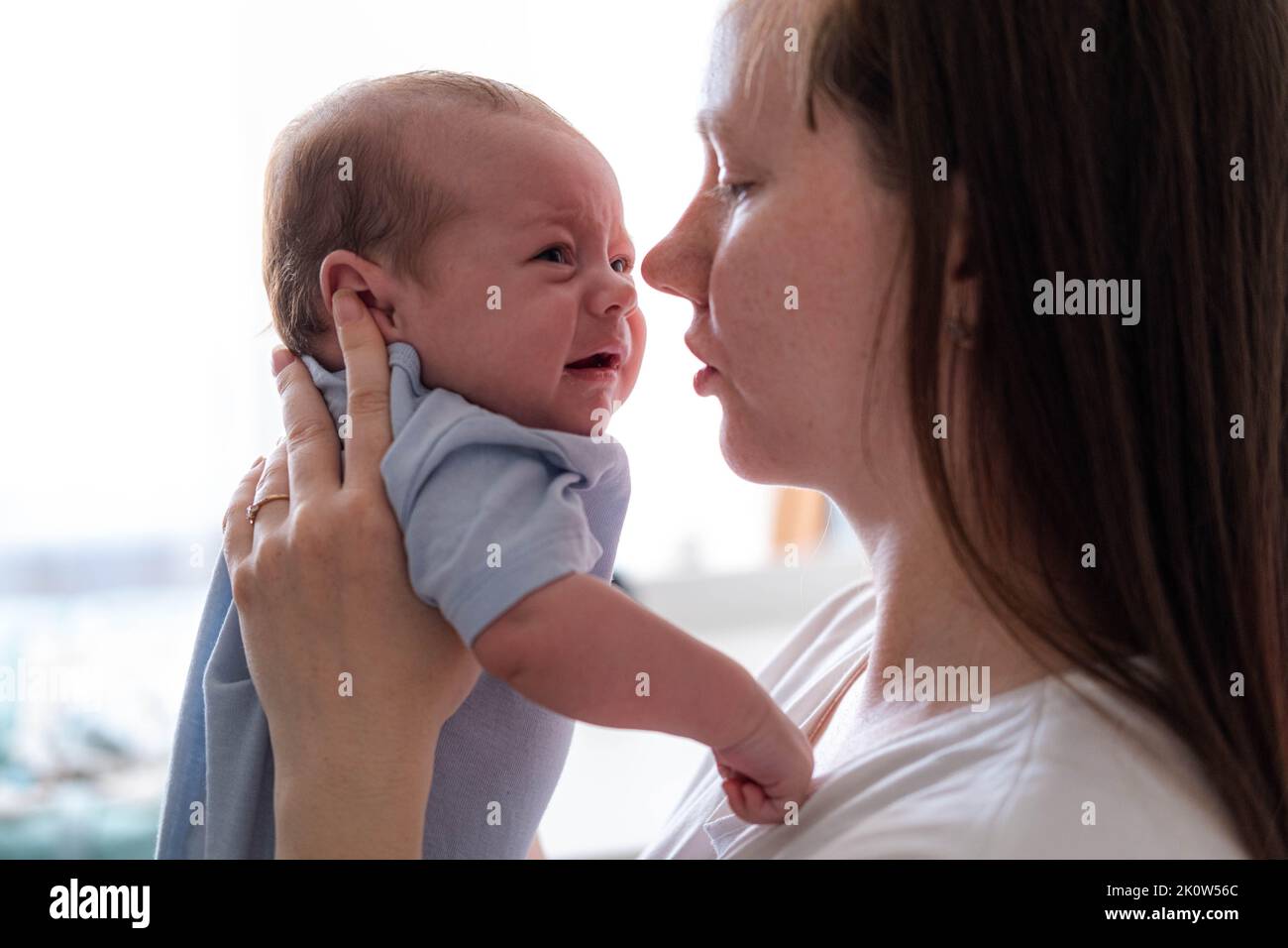 Mommy tries to calm the crying baby, shakes him in her arms ...