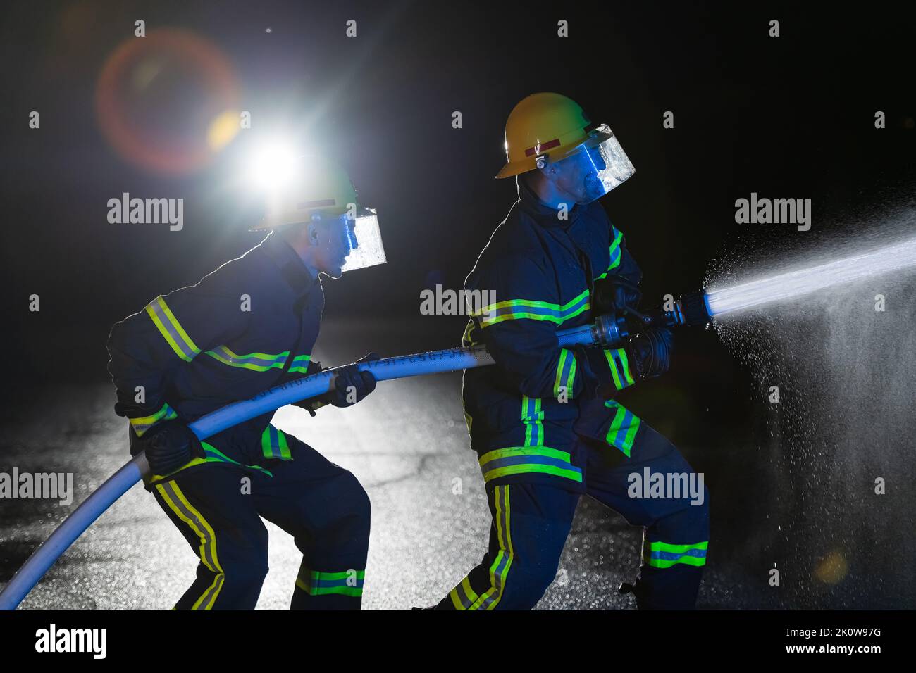 Firefighters use a water hose to eliminate a fire hazard. Team of ...