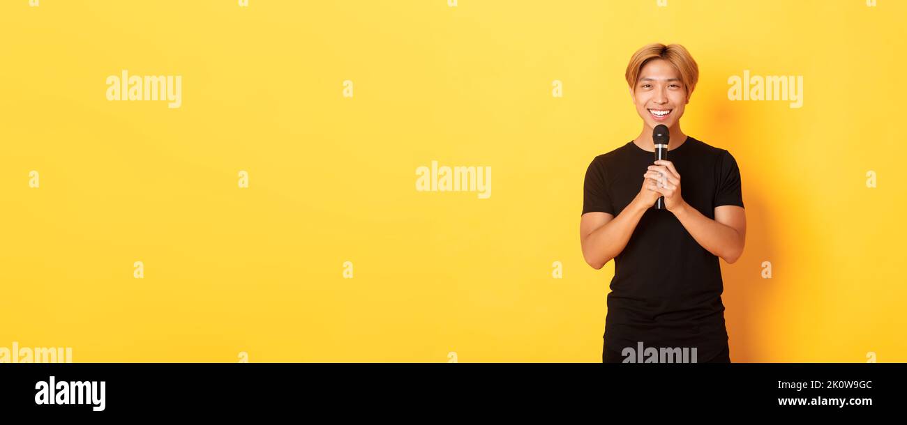 Portrait of charismatic smiling asian man holding microphone and ...