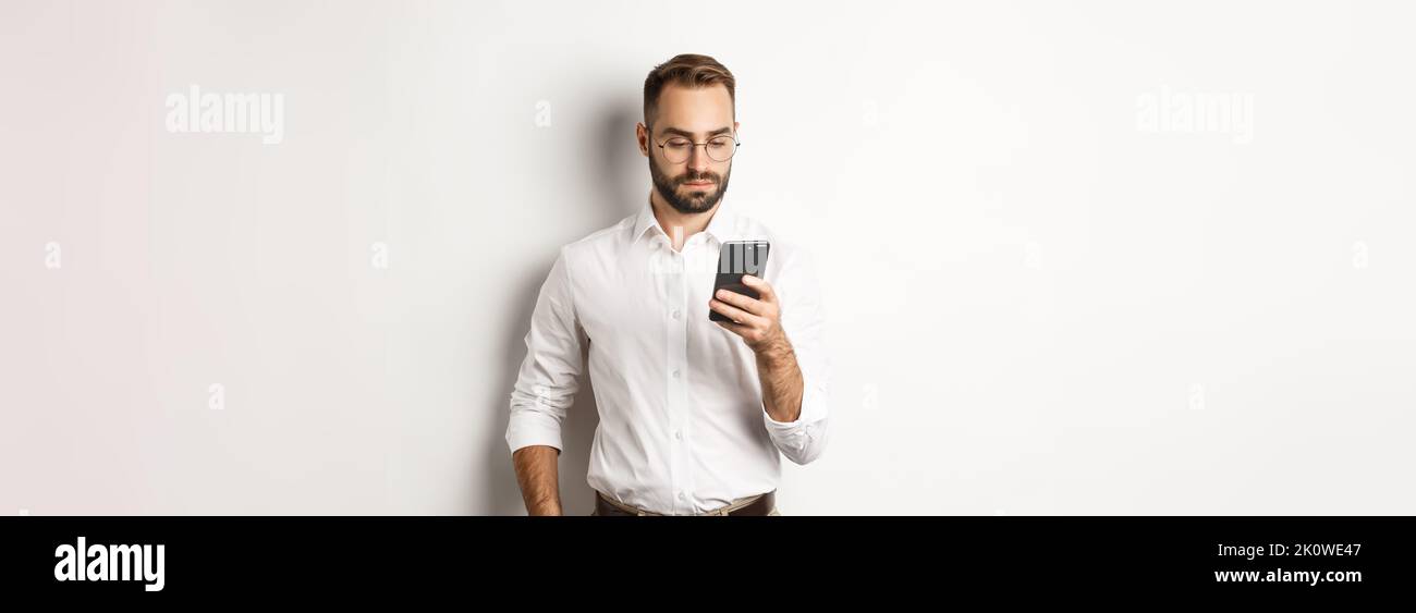 Businessman reading message on phone, standing over white background ...