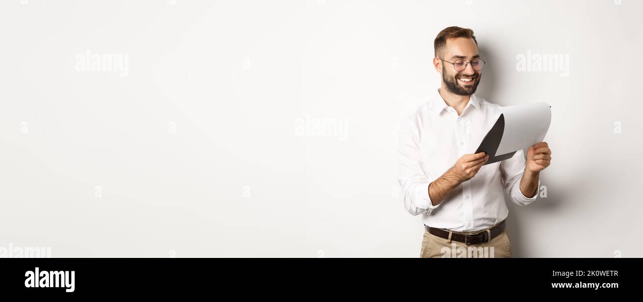 Businessman looking satisfied at documents, reading report and smiling ...