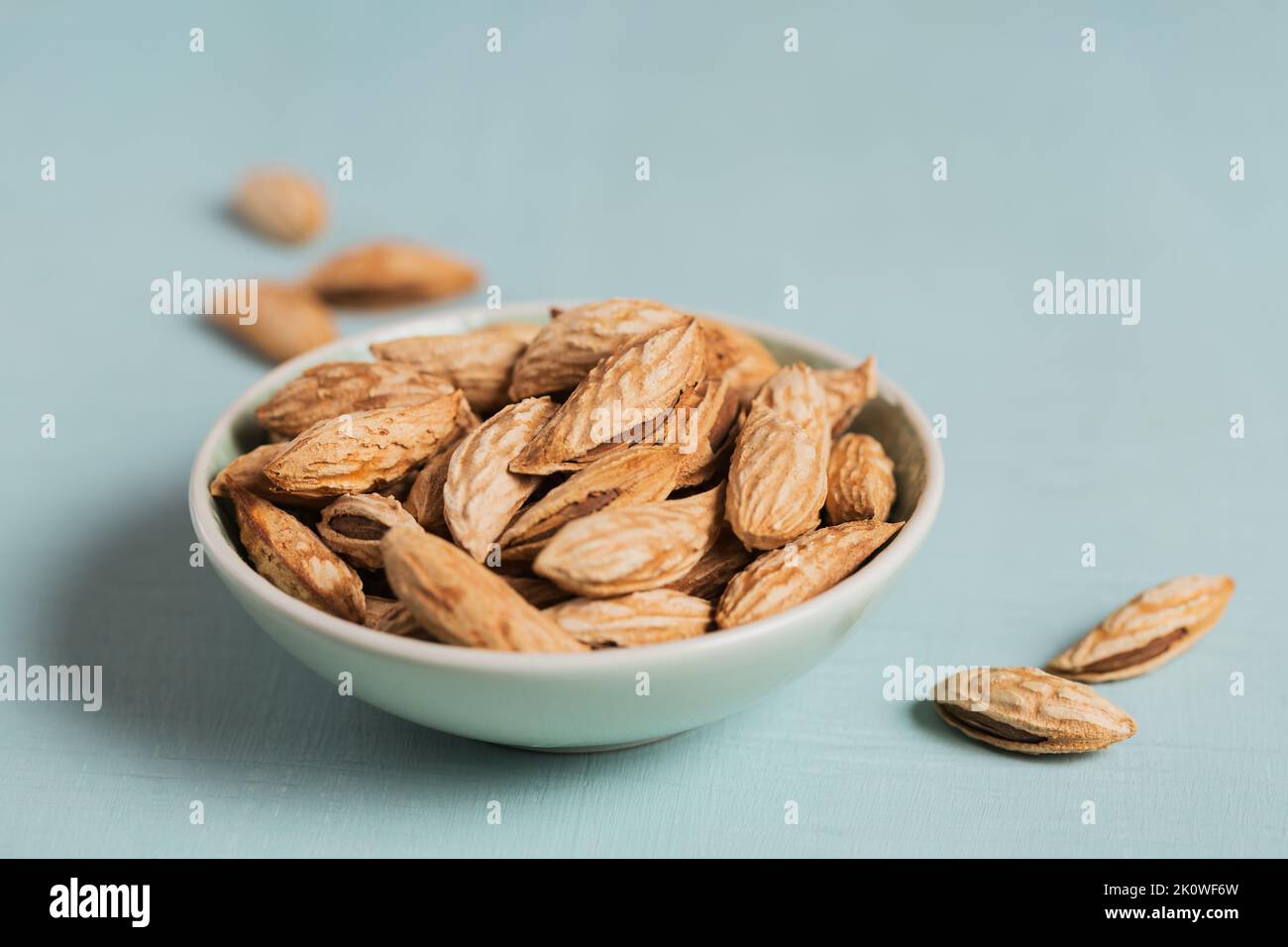 Pile of Almond nuts in a bowl on a light blue background Stock Photo ...
