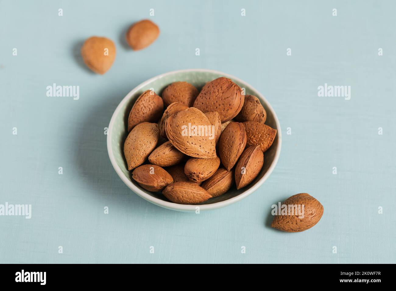 Pile of Almond nuts in a bowl on a light blue background Stock Photo ...