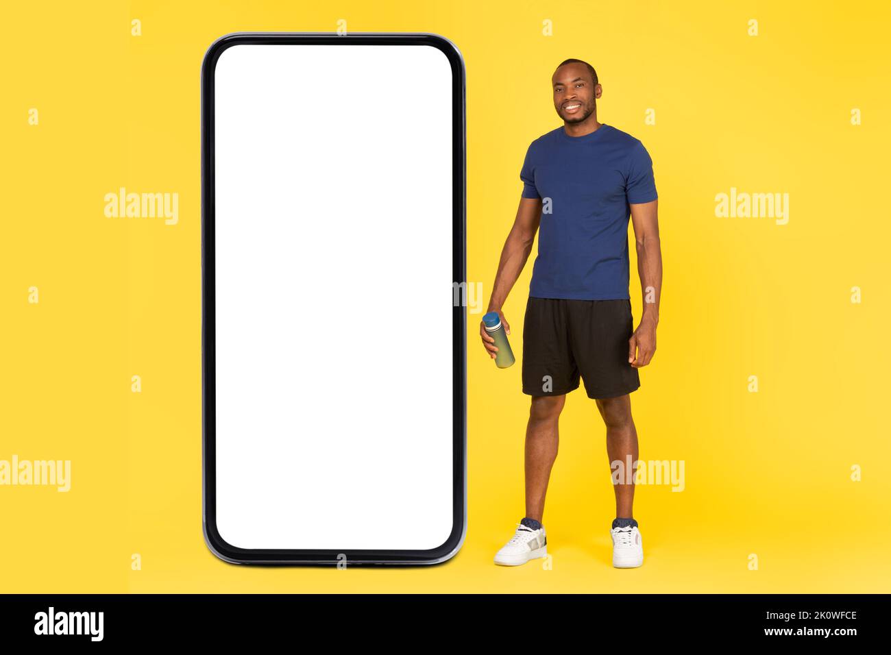 Sporty Black Male Posing Near Phone Large Screen, Yellow Background ...