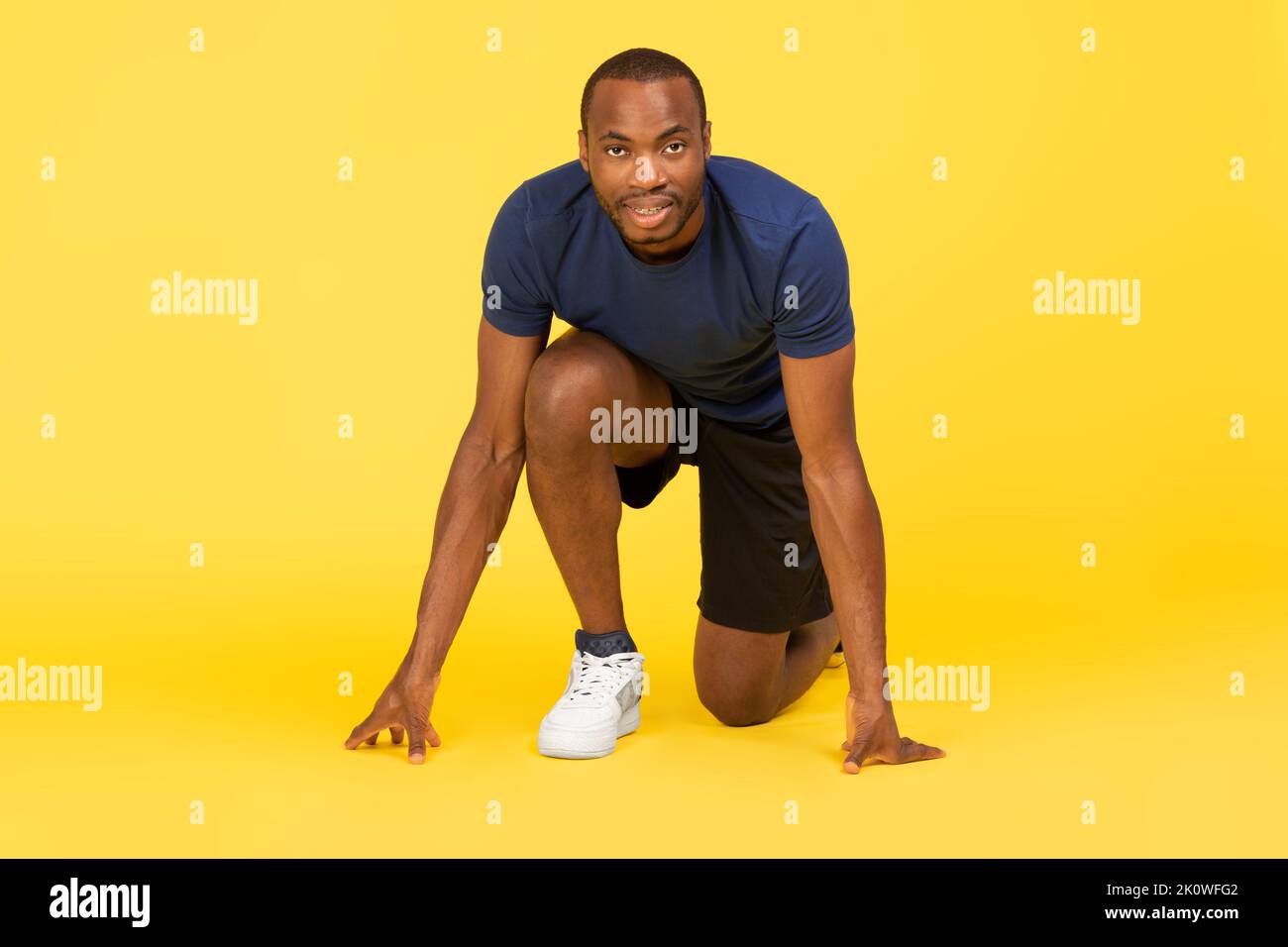 African Male Runner Standing In Crouch Start Position, Yellow ...