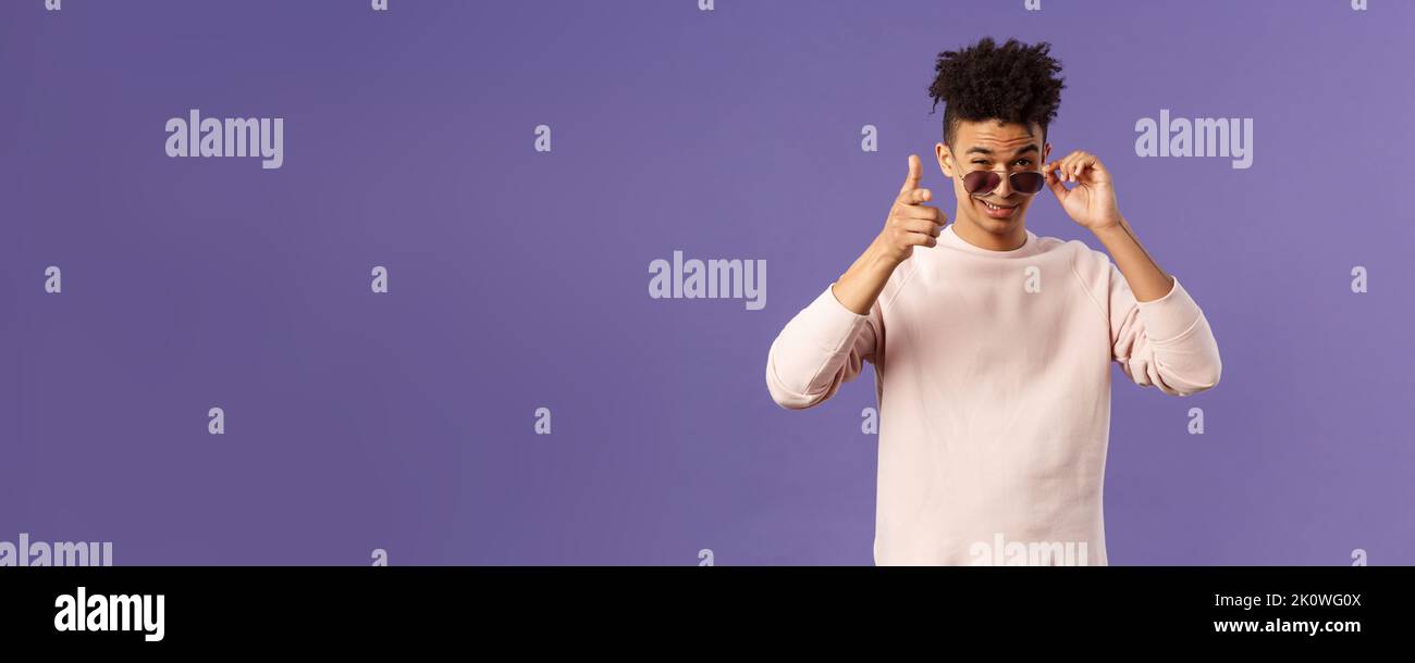 Portrait of cheeky handsome young man wearing sunglasses, take them off ...