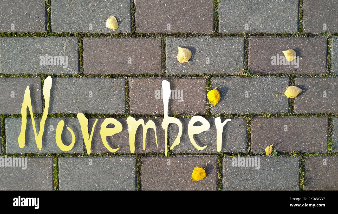 Yellow and white inscription November on background of gray brick road ...