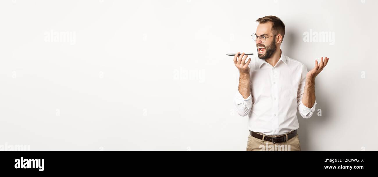 Angry business man shouting at speakerphone, record voice message in ...