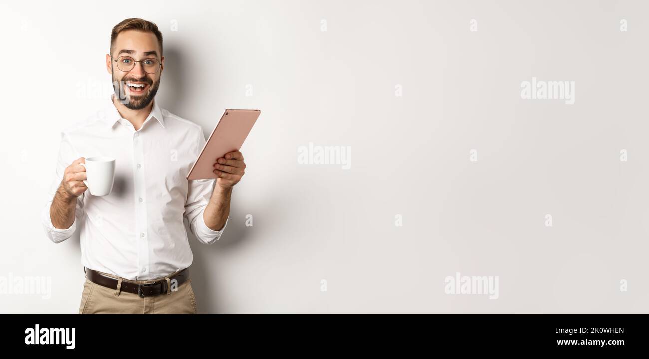 Excited manager reading on digital tablet, working and drinking coffee ...