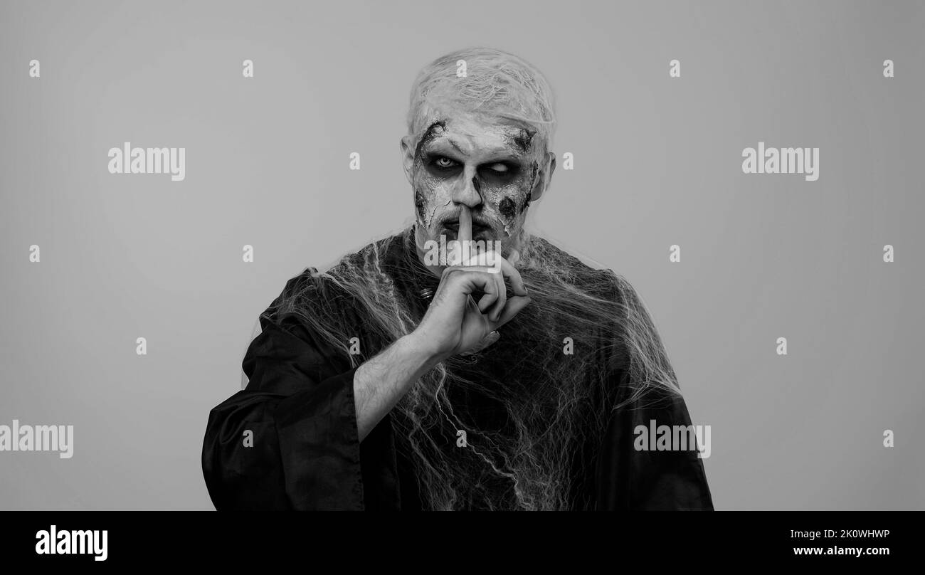 Shh be quiet. Sinister man with horrible scary Halloween zombie makeup ...