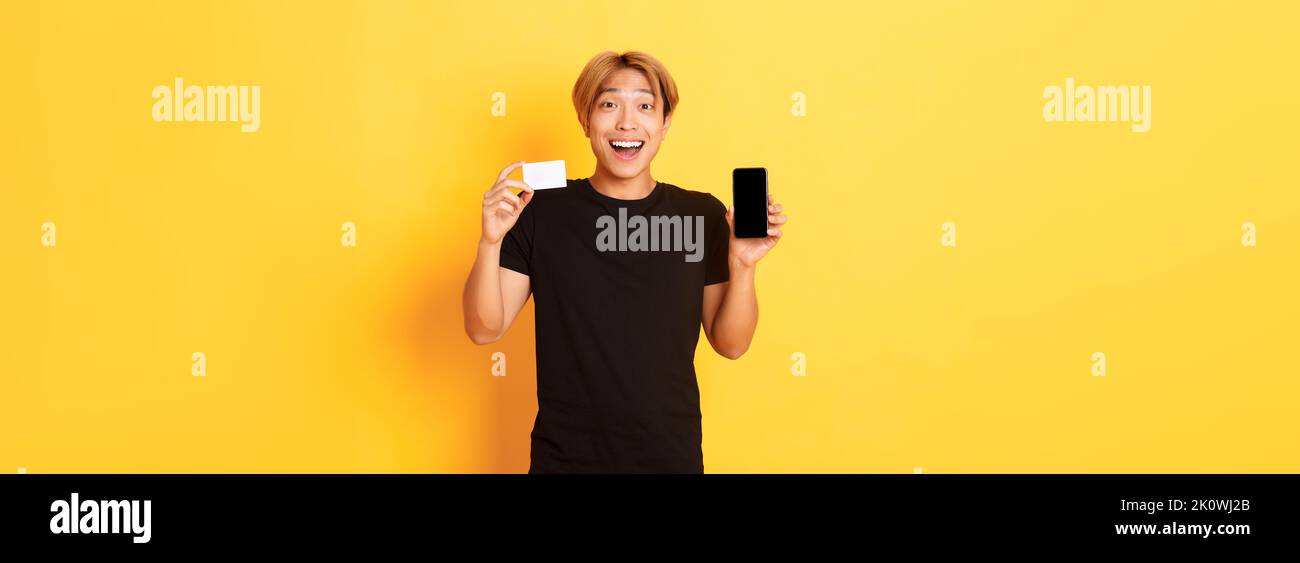 Portrait of excited happy asian man showing mobile phone screen and ...