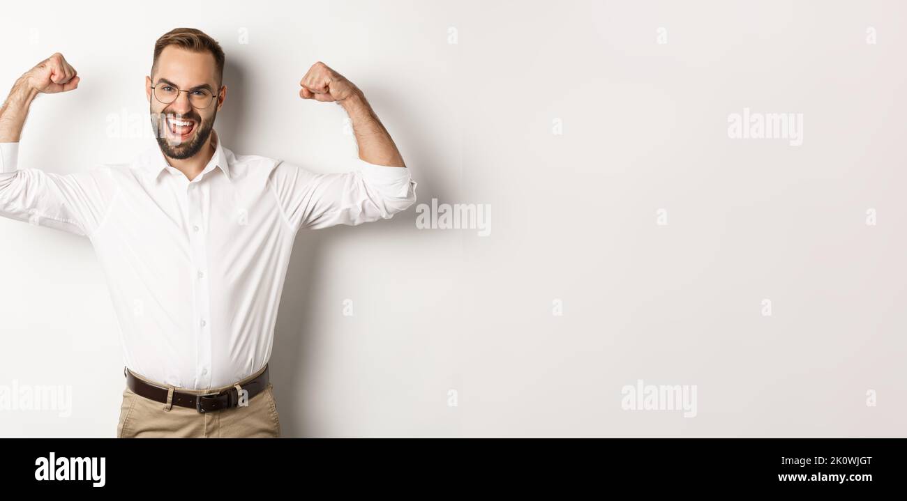 Successful manager flex biceps, showing muscles and looking confident ...