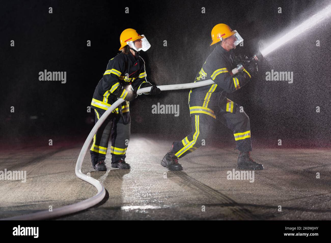 Firefighters using a water hose to eliminate a fire hazard. Team of ...