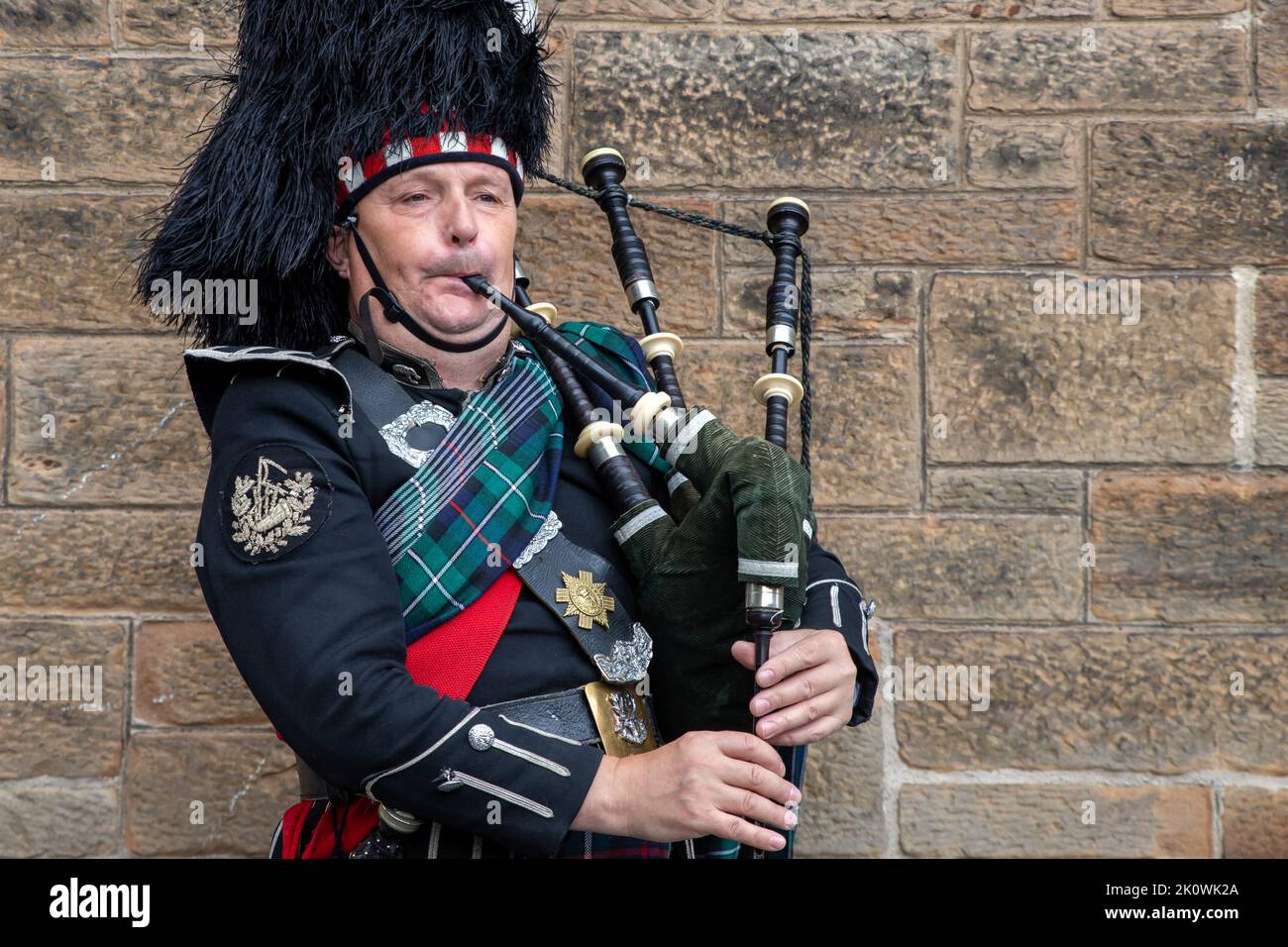 A musician in traditional Scottish attire plays the bagpipes on Royal ...