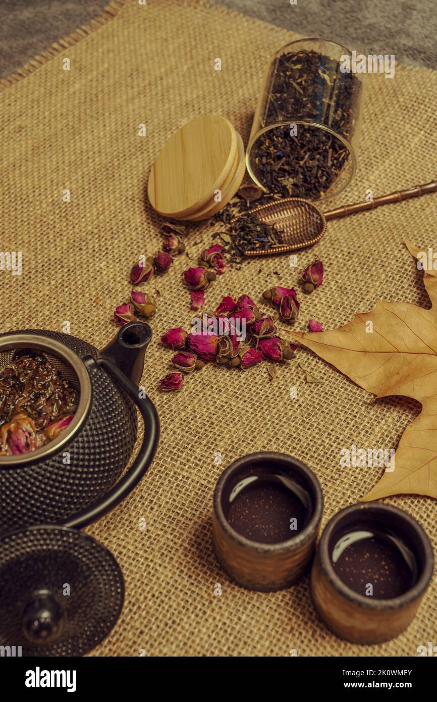 Black Japanese teapot, glasses with tea, container with tea and Roses ...