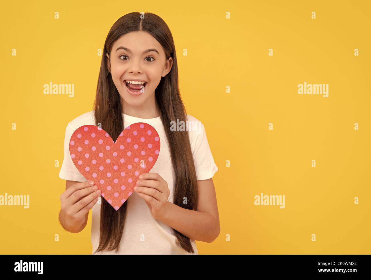 amazed teen girl holding valentines heart on yellow background ...