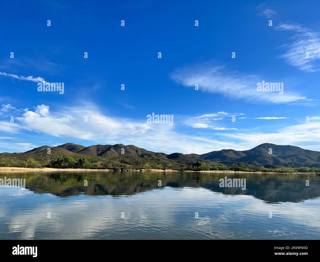 A beautiful view of a reflective lake and mountains under the blue sky ...