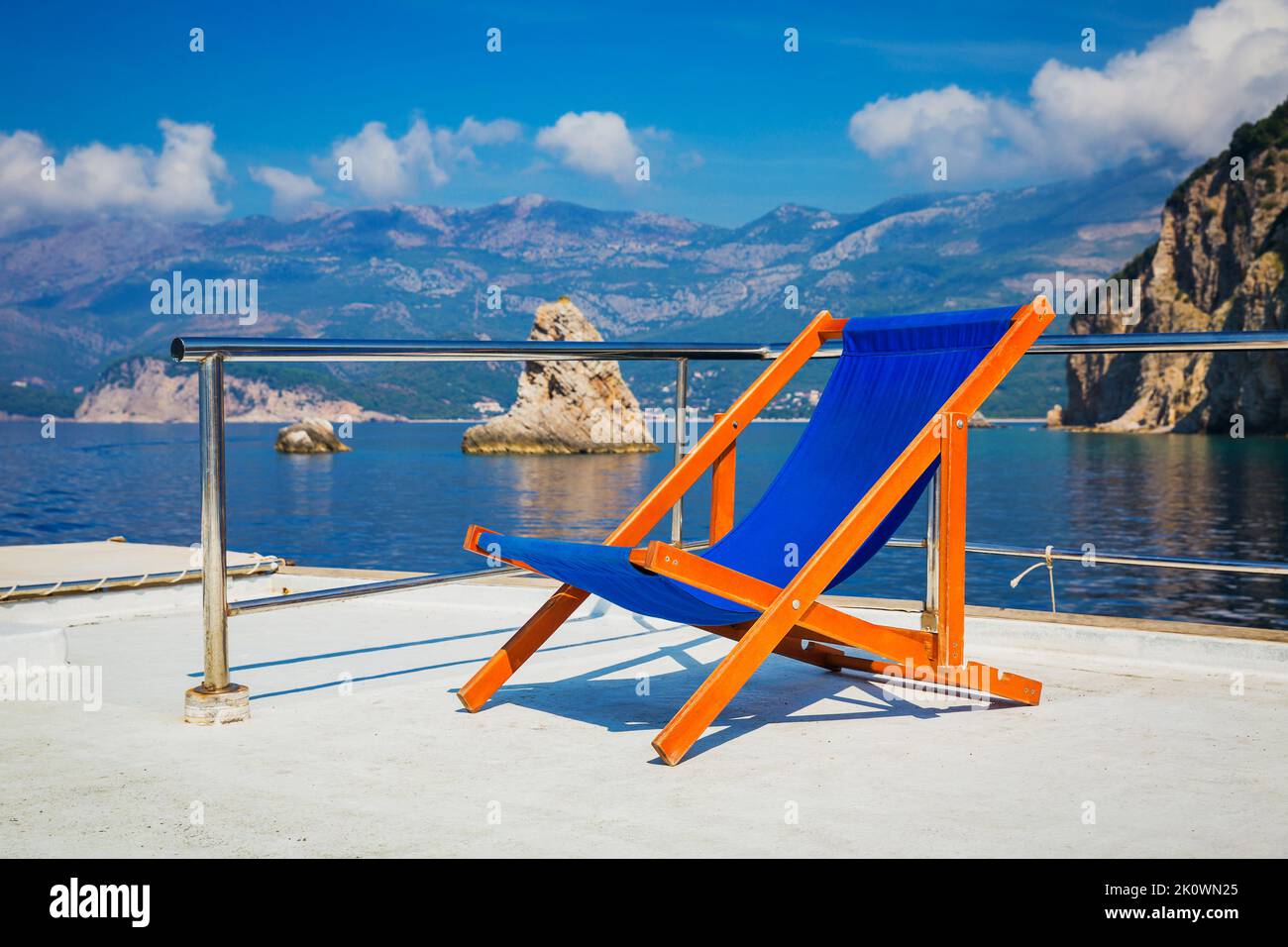 View over the board of a boat on sea and grey rock islands with sun ...