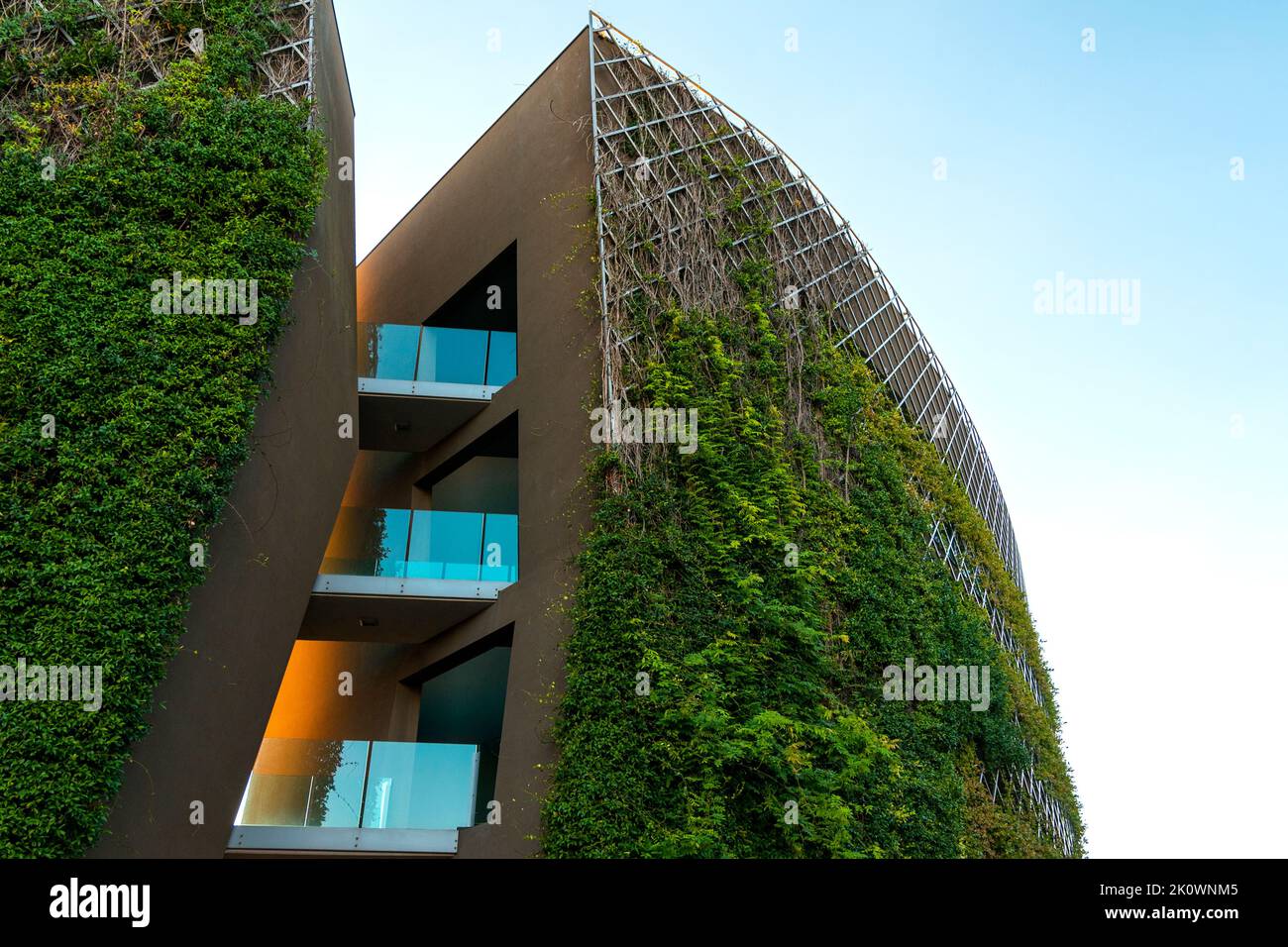 The building is overgrown with plants. Plant facade on a modern ...