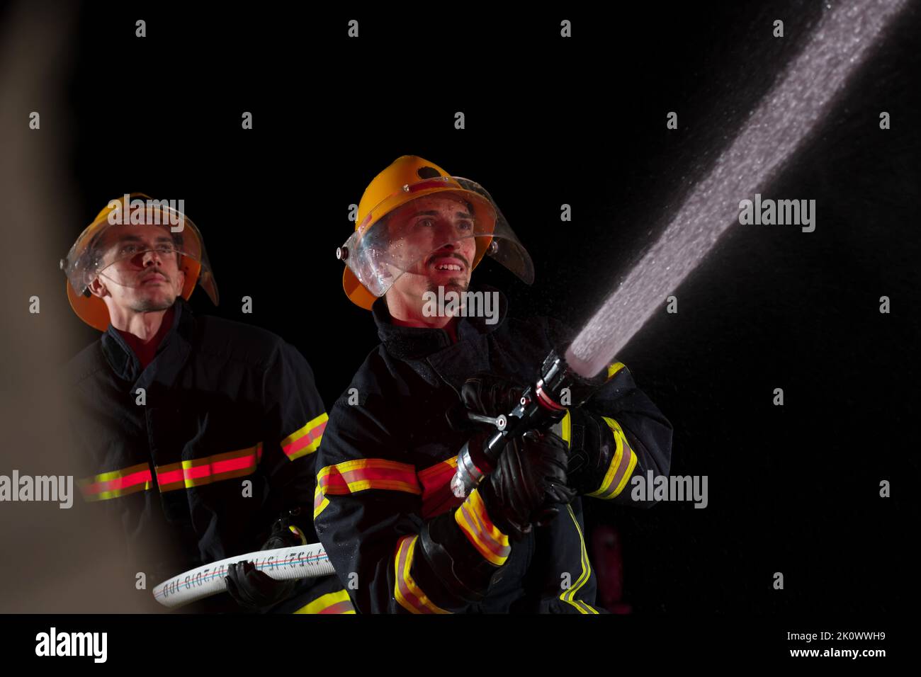 Firefighters use a water hose to eliminate a fire hazard. Team of ...