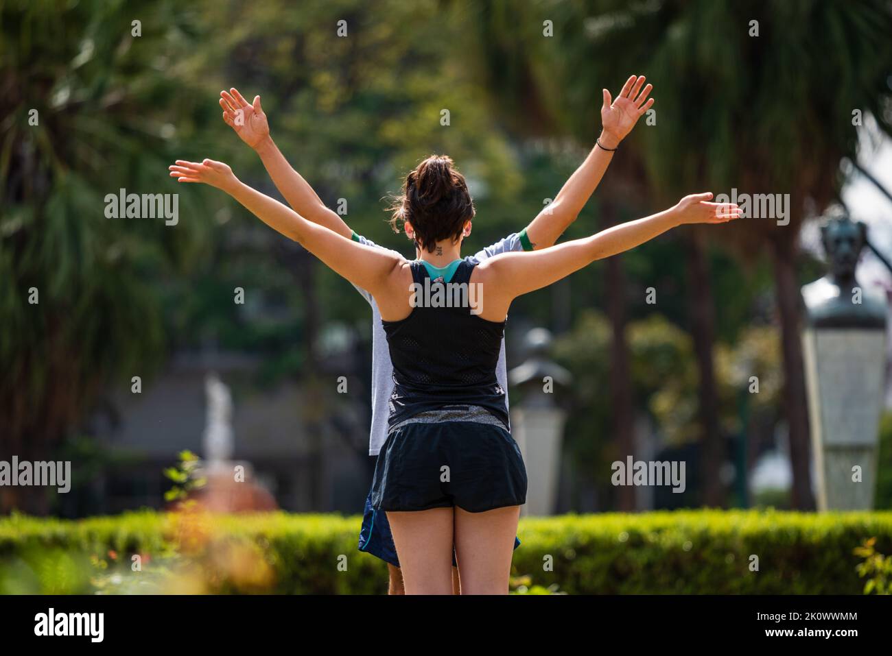 Couple doing yoga pose with arms raised at Praça da Liberdade in Belo ...