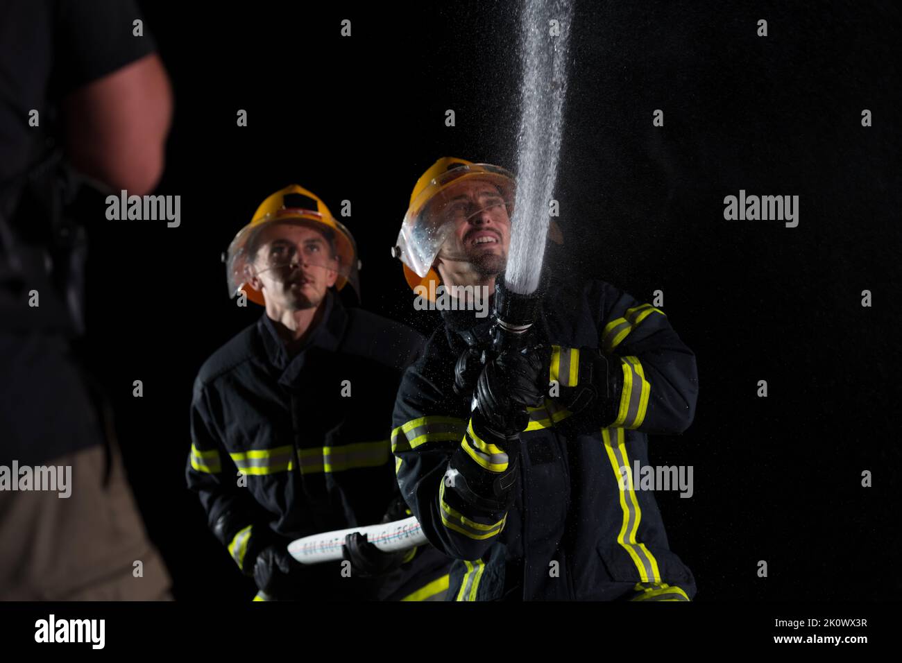 Firefighters use a water hose to eliminate a fire hazard. Team of ...