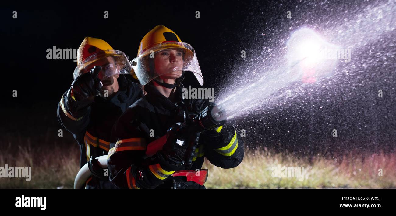 Firefighters using a water hose to eliminate a fire hazard. Team of ...