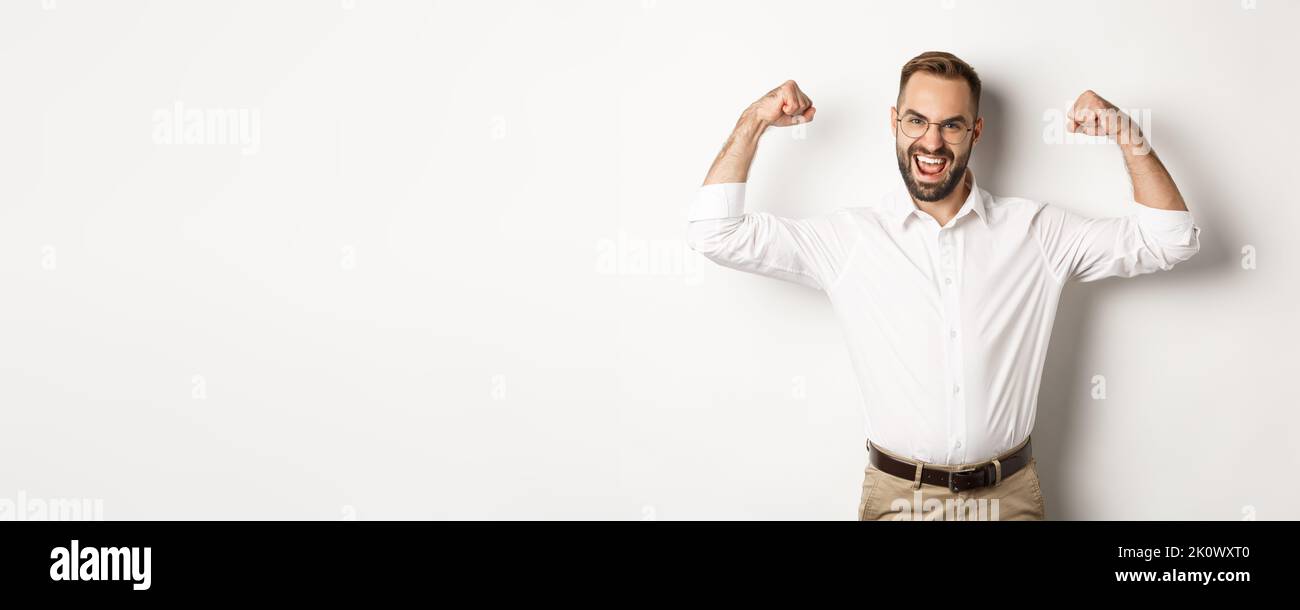 Successful manager flex biceps, showing muscles and looking confident ...