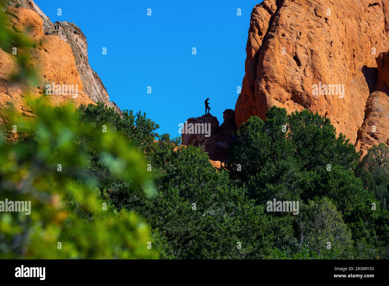 The silhouette of a person standing on a rock pinnacle between to red ...