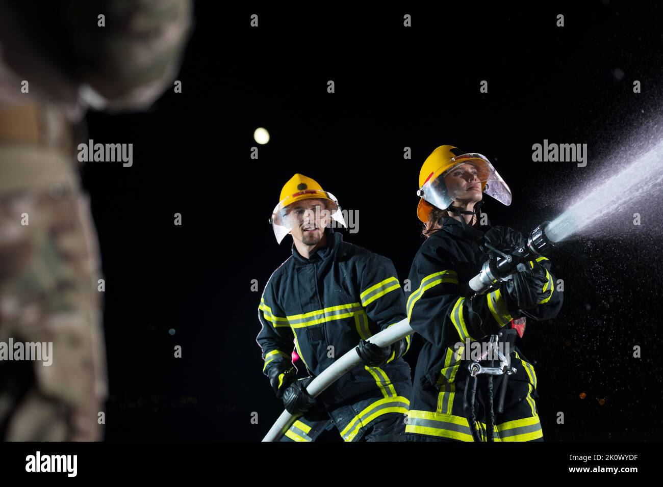 Firefighters using a water hose to eliminate a fire hazard. Team of ...