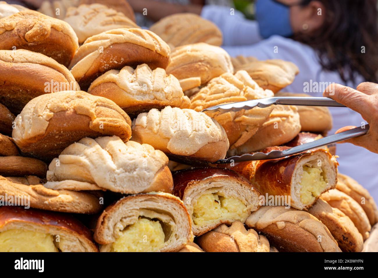 Mexican sweet bread, woman taking a loaf of bread from a basket with ...