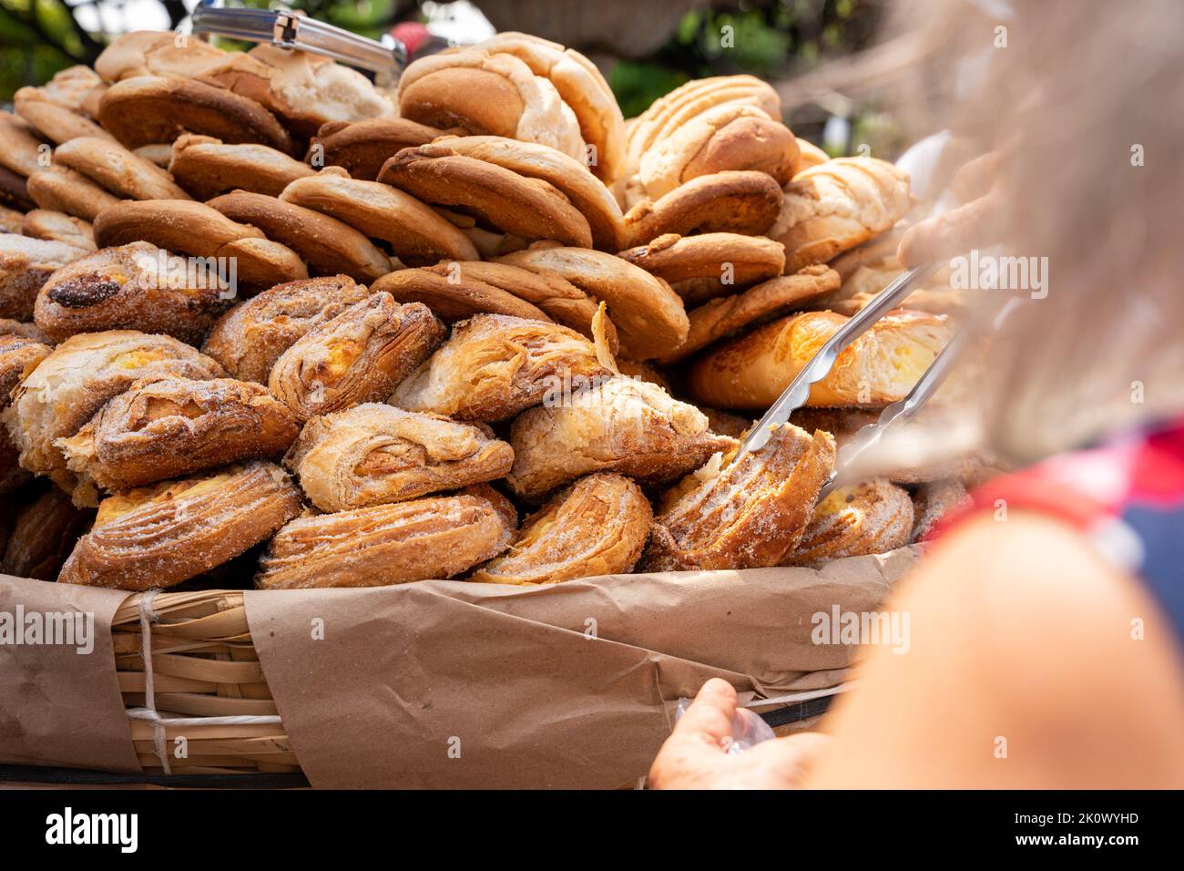 Mexican sweet bread, woman taking a loaf of bread from a basket with ...
