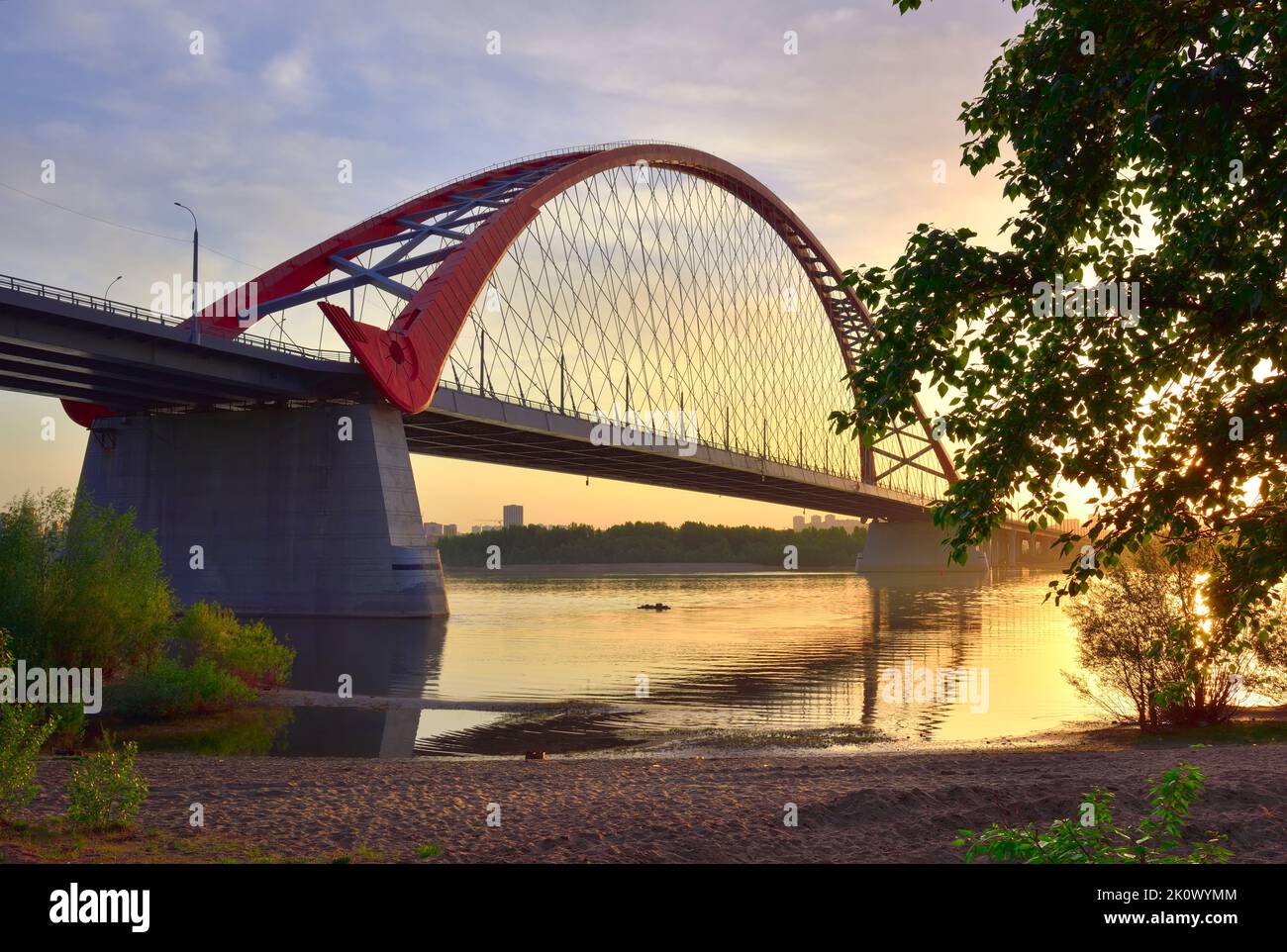 A large arched bridge at dawn. Bugrinsky bridge over the Ob River among ...