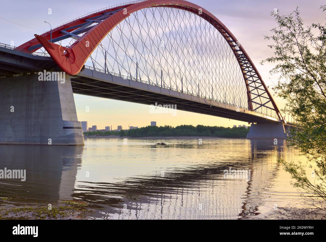 A large arched bridge at dawn. Bugrinsky bridge over the Ob River among ...