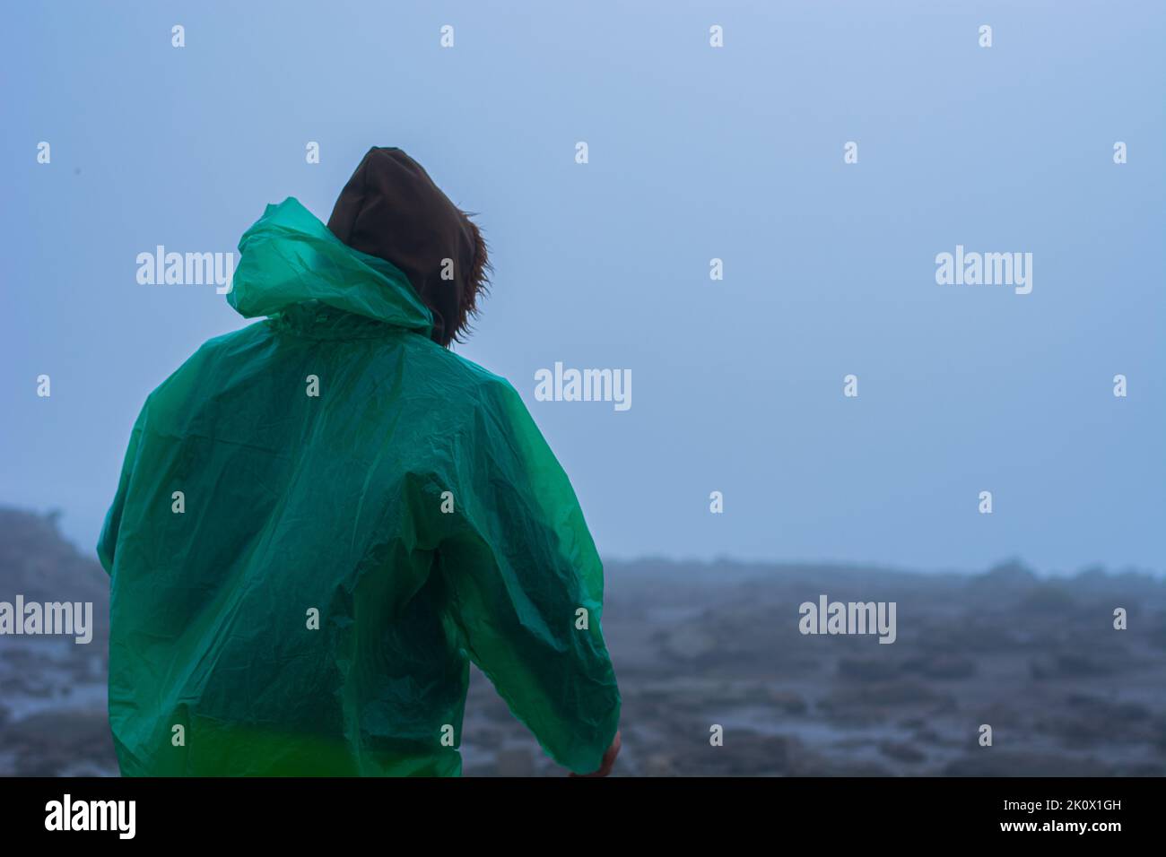 A man from the back wearing a plastic raining suit and looking from a ...