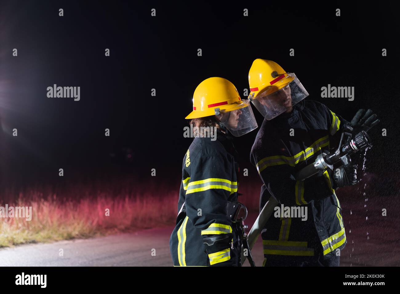 Firefighters using a water hose to eliminate a fire hazard. Team of ...