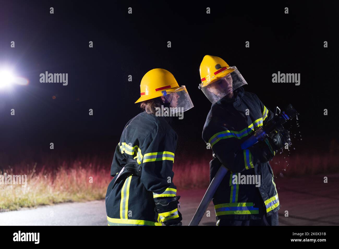 Firefighters using a water hose to eliminate a fire hazard. Team of ...