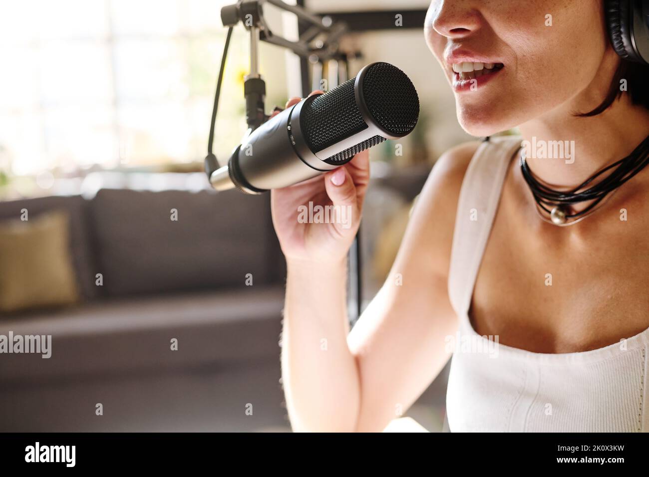 Close-up of young modern host in white tanktop speaking in microphone ...