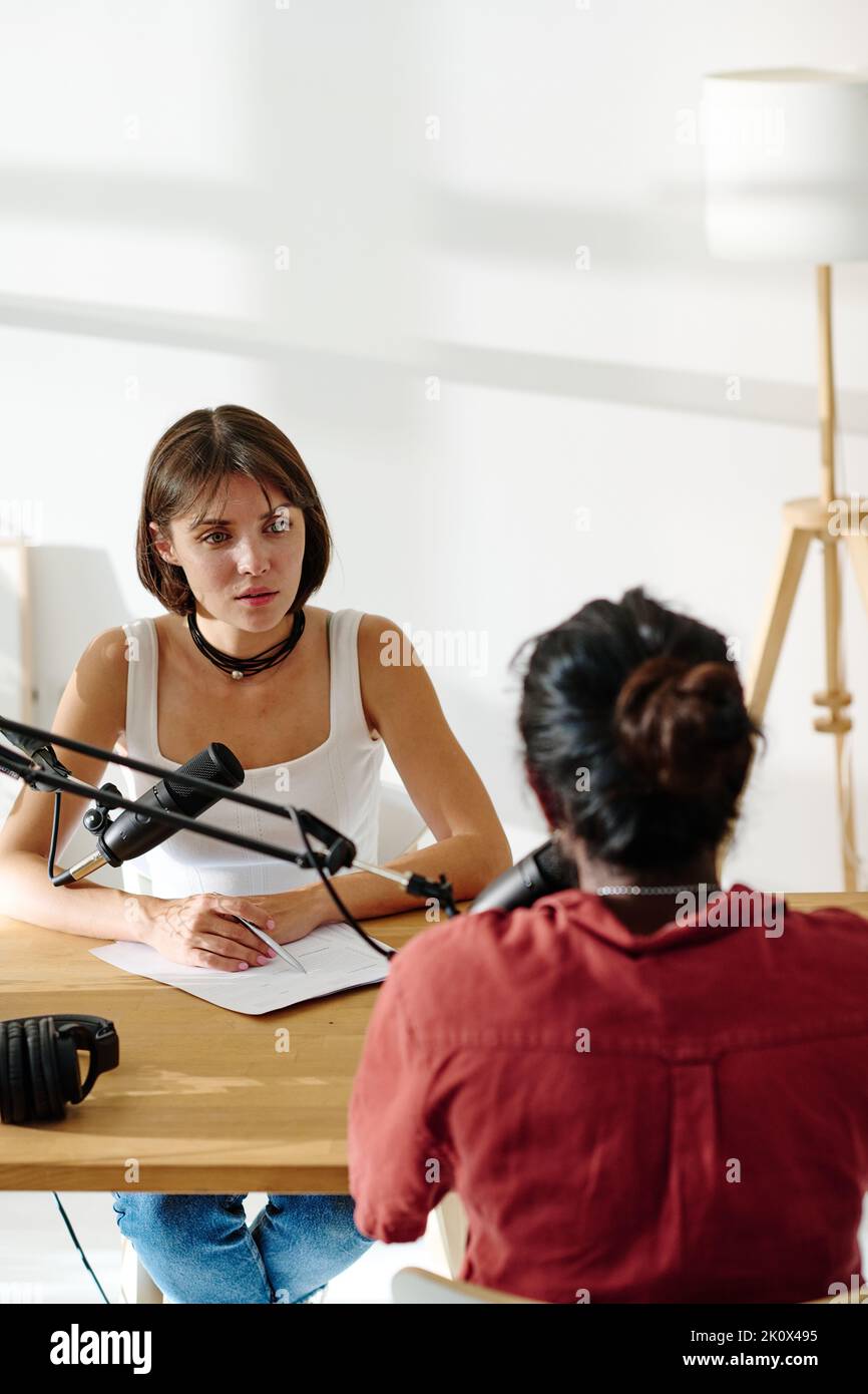 Young brunette woman with plan of discussion pointing at paper and ...