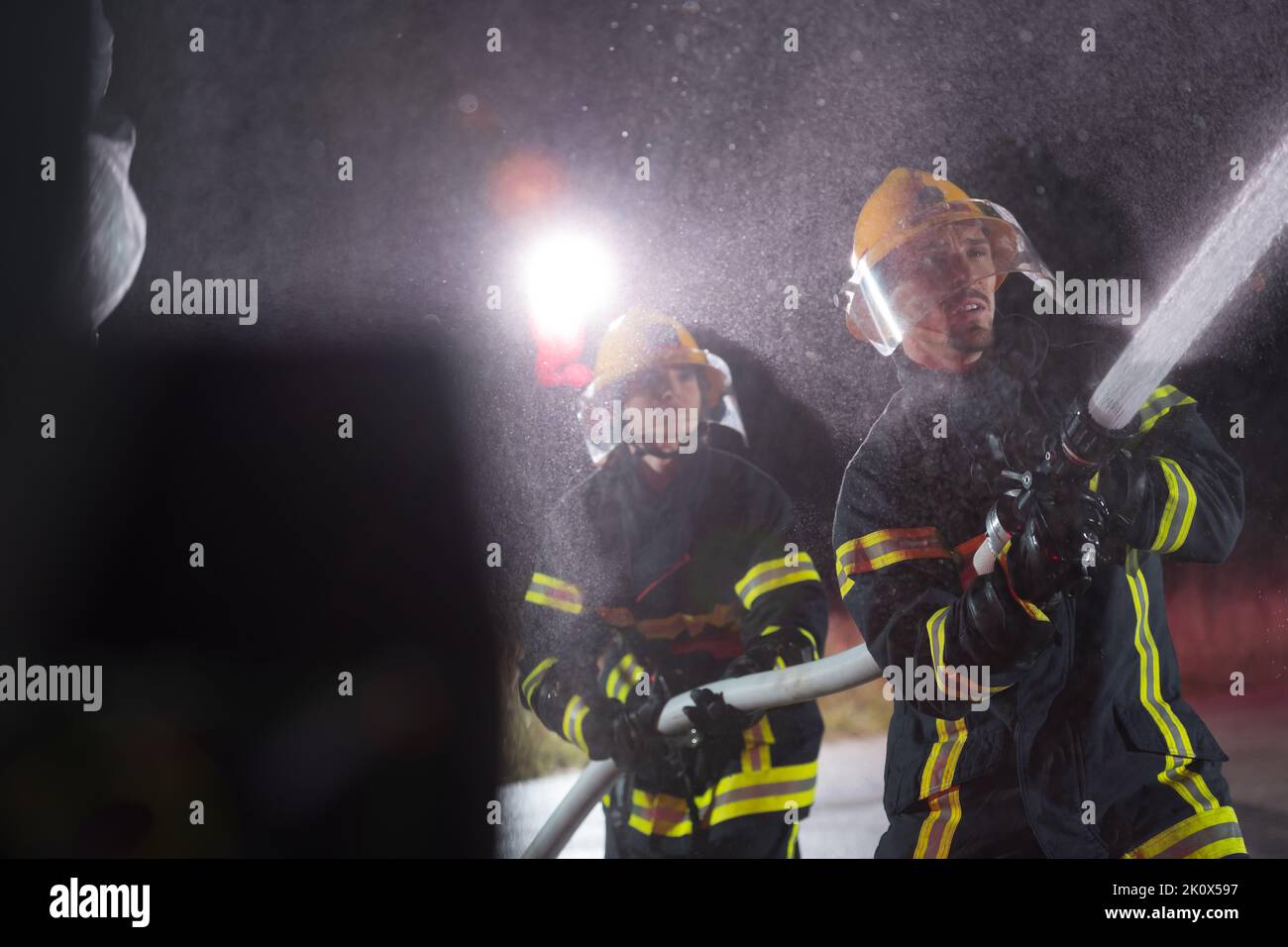 Firefighters using a water hose to eliminate a fire hazard. Team of ...