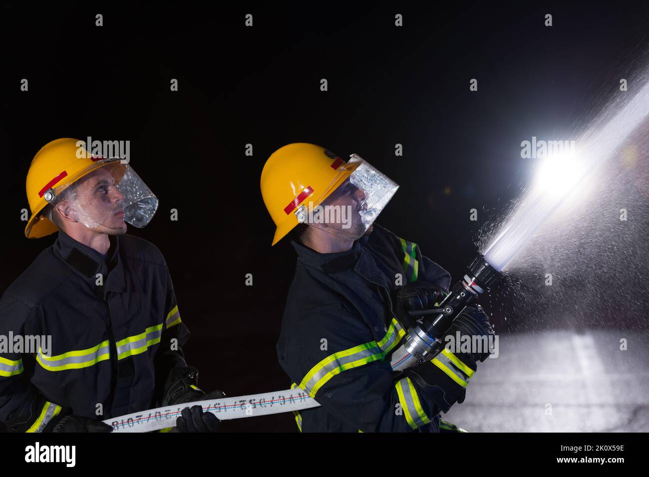 Firefighters use a water hose to eliminate a fire hazard. Team of ...