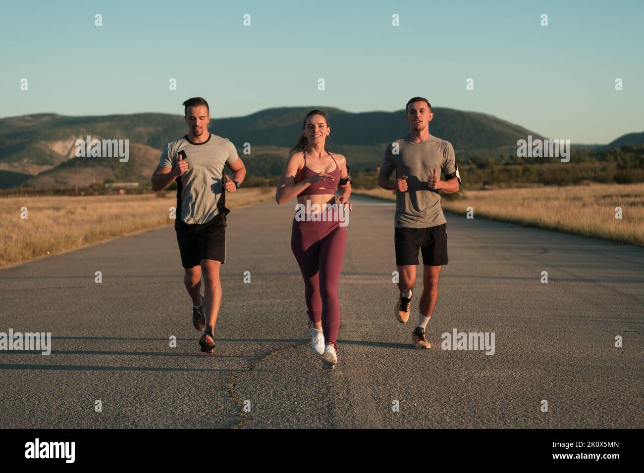 Three runners sprinting outdoors - Sportive people training in a urban ...
