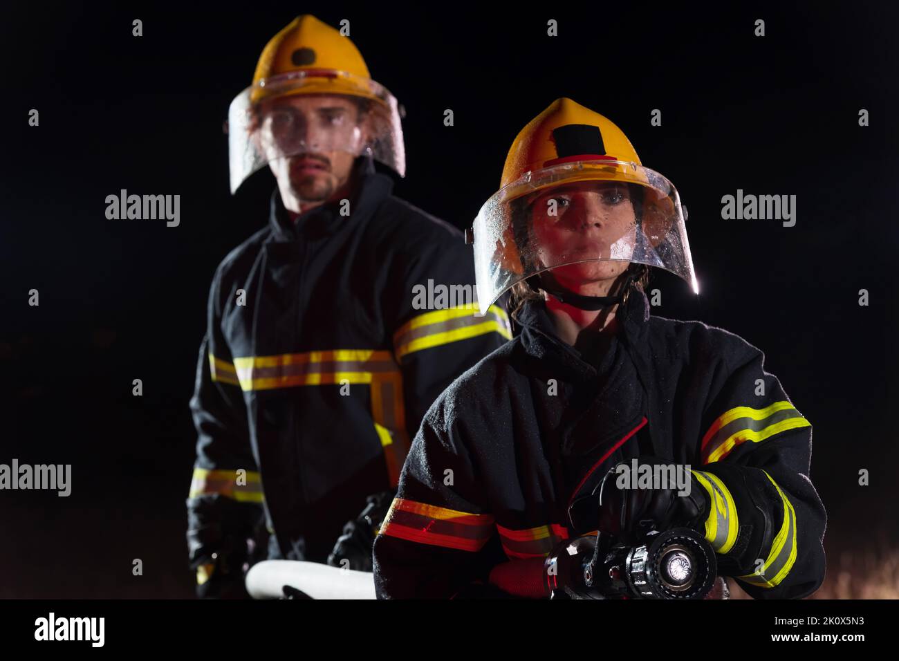 Firefighters using a water hose to eliminate a fire hazard. Team of ...