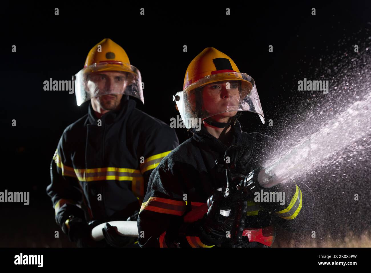 Firefighters using a water hose to eliminate a fire hazard. Team of ...