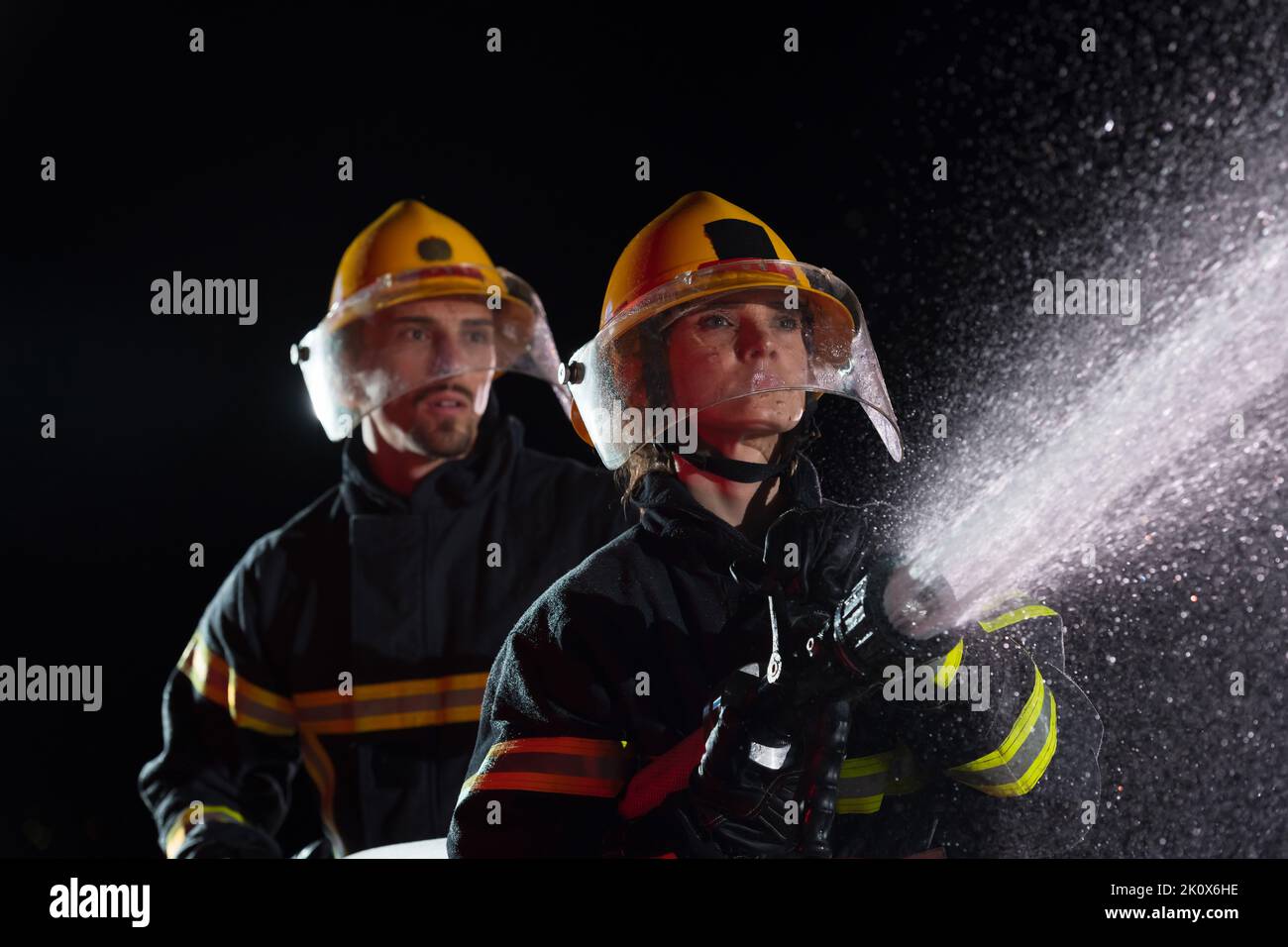 Firefighters using a water hose to eliminate a fire hazard. Team of ...