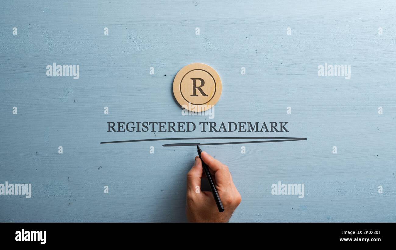 Letter R cut into wooden cut circle and male hand writing a Registered ...