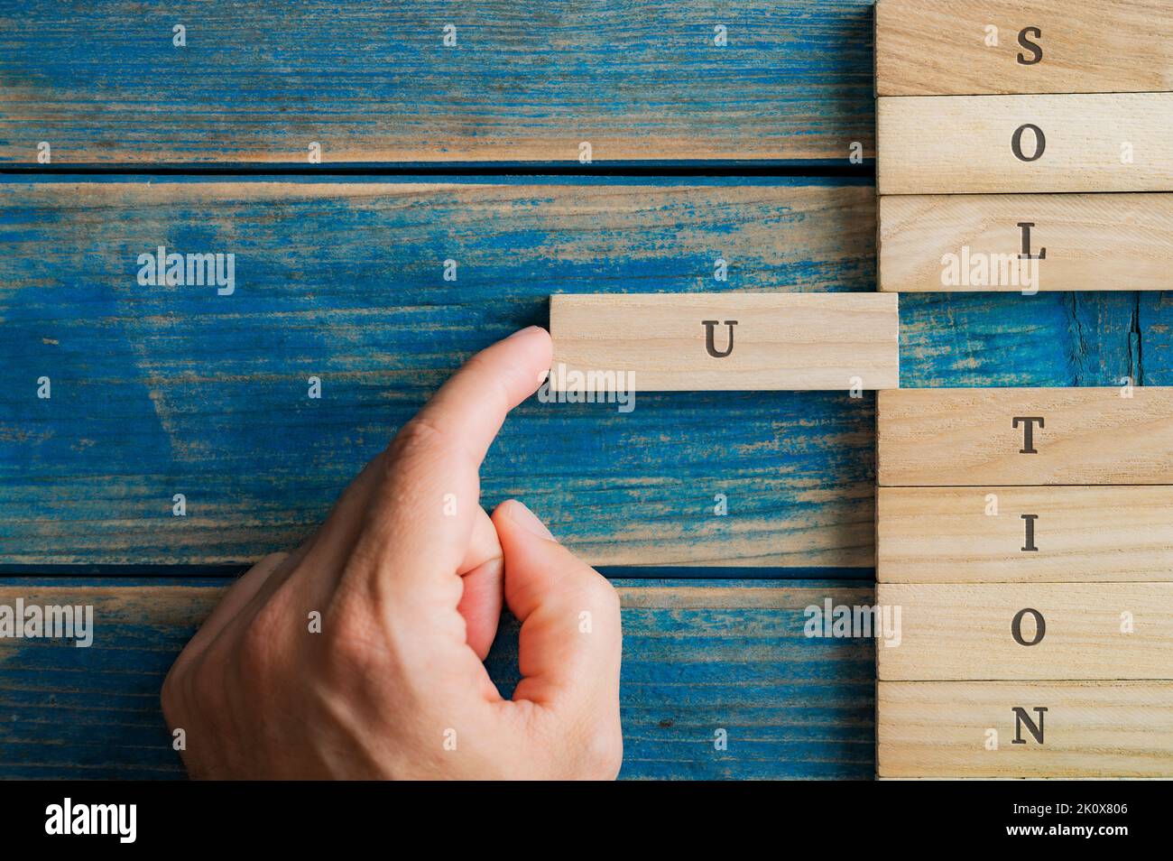 Male hand pushing a wooden peg into a stack of them to spell the word ...